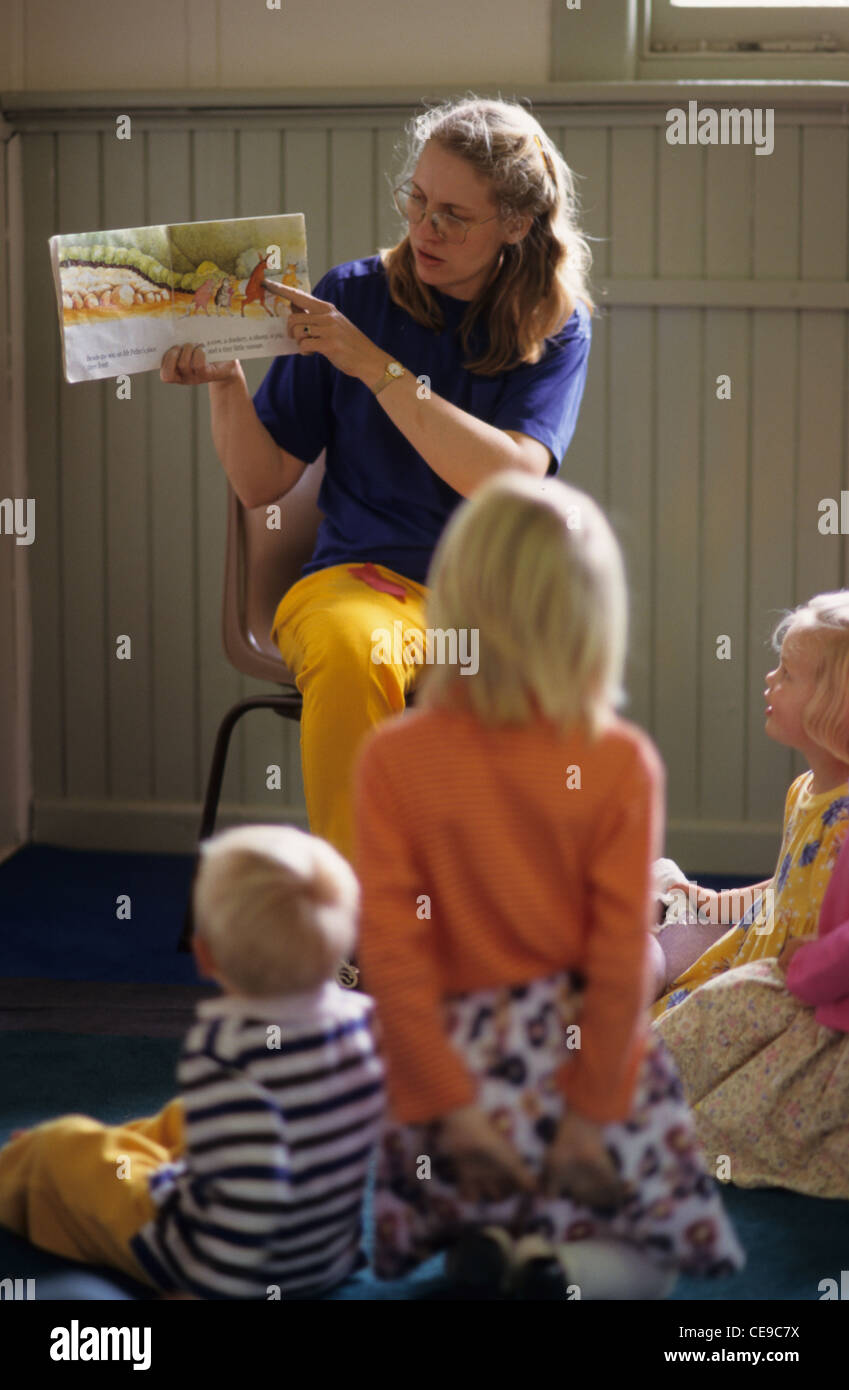 Teaching to read, teacher in class pointing to book Stock Photo - Alamy