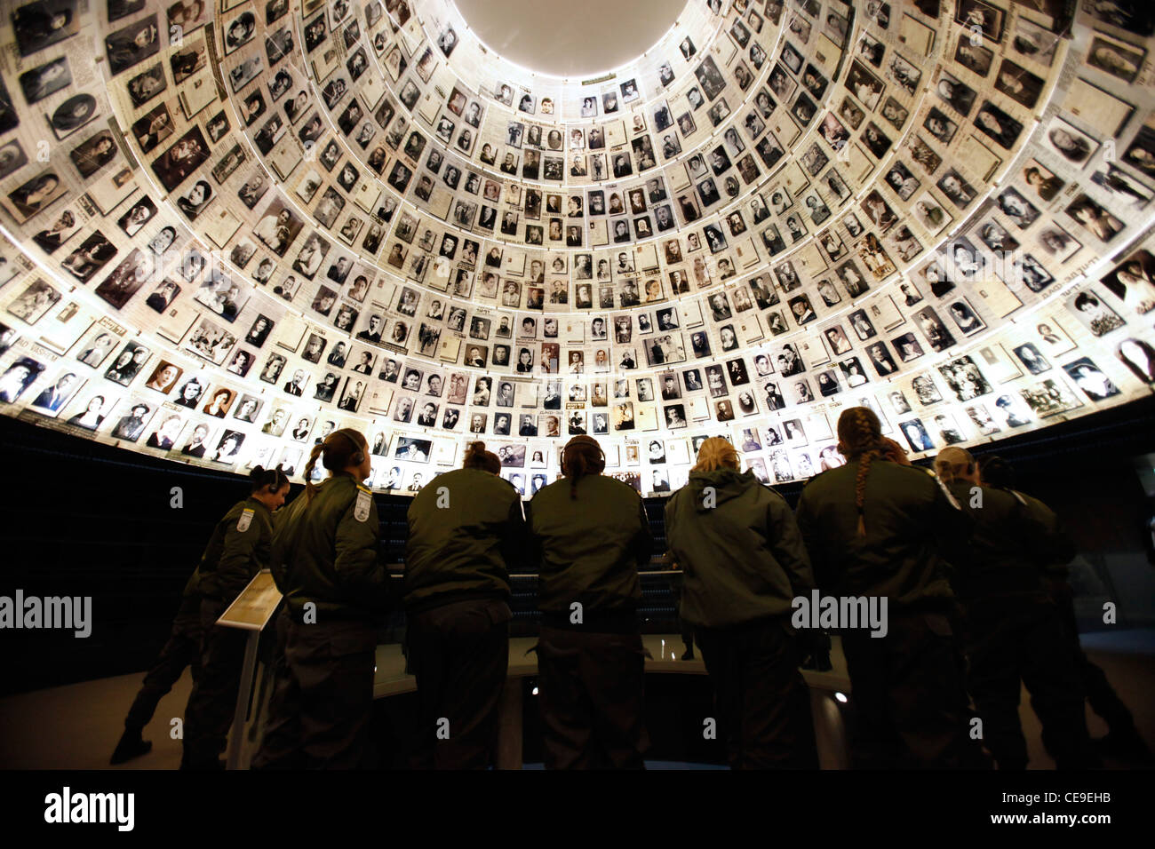 Israeli female soldiers look up and around at portraits of Holocaust ...