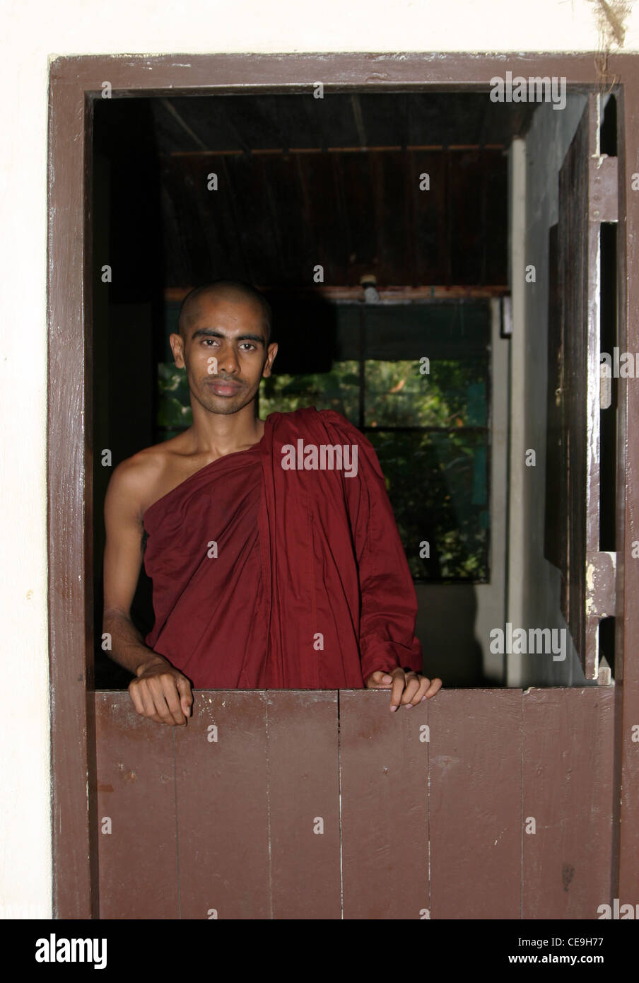 A Buddhist Monk looks out from behind a door in a temple in Sri Lanka ...