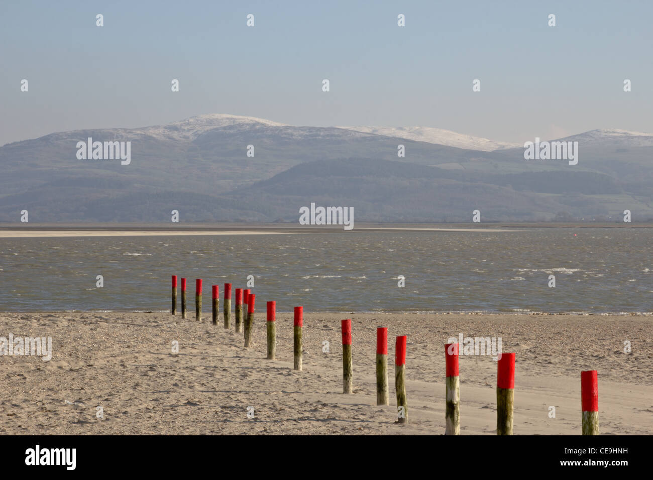 Dyfi Estuary at low tide with red capped warning stakes and snow capped ...
