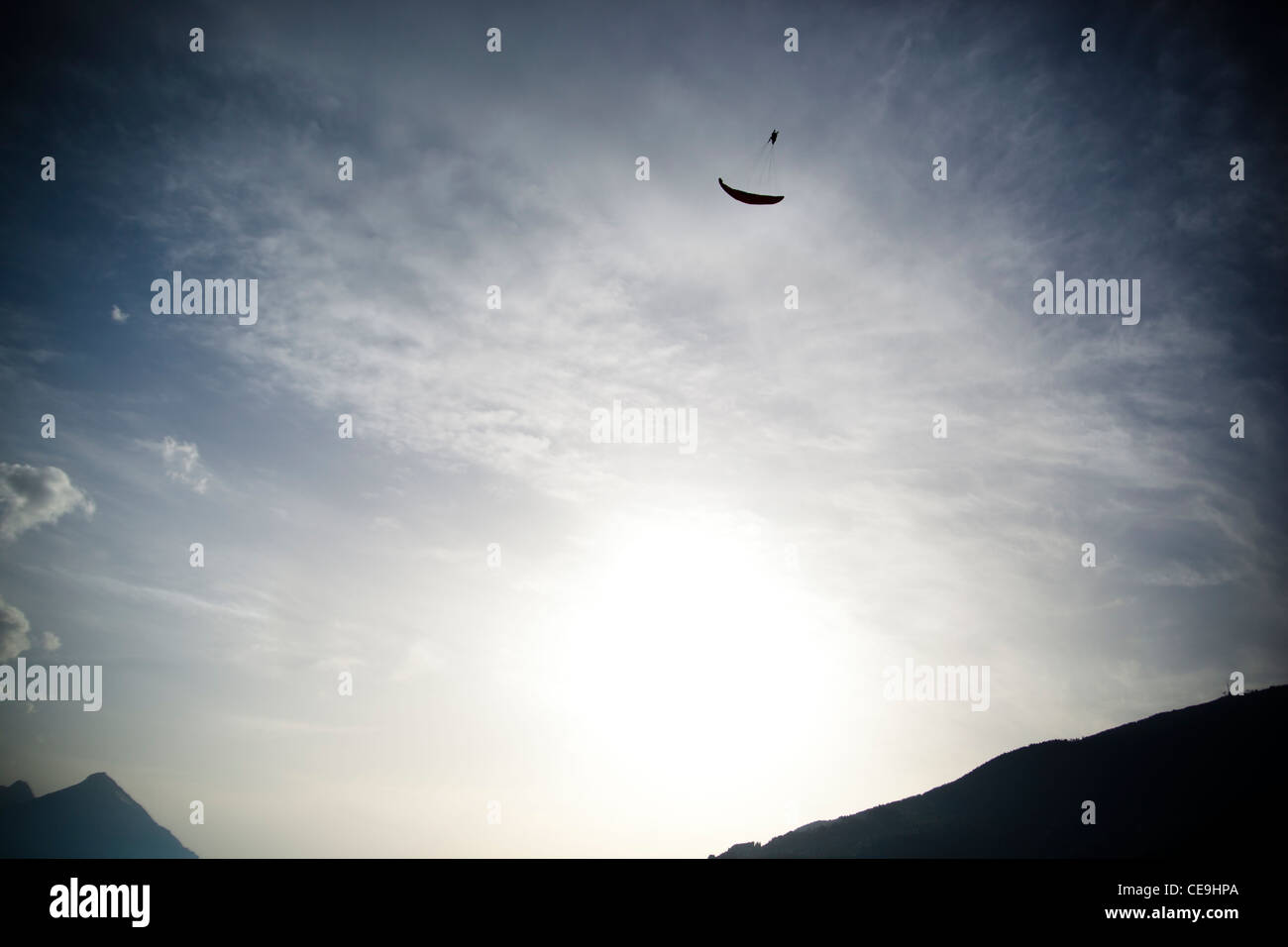 Acro paraglider pilot performing tricks over Interlaken at sunset ...