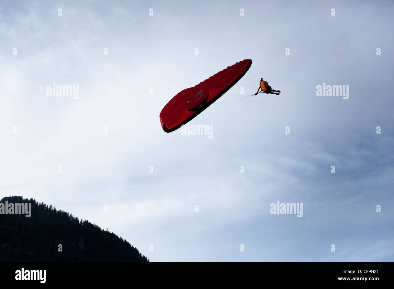Acro paraglider pilot performing tricks over Interlaken in the evening ...