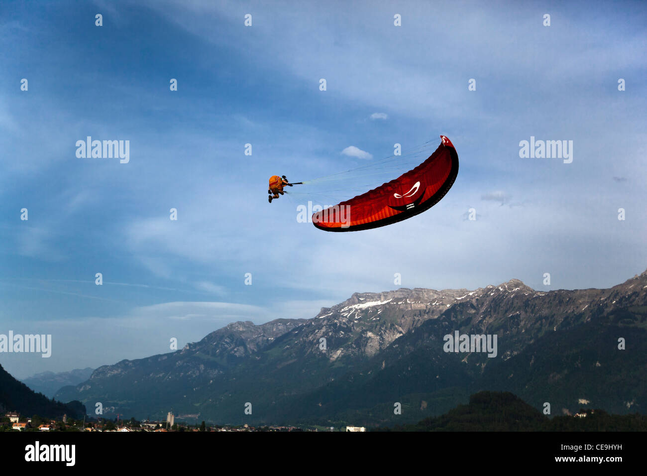 Acro paraglider pilot performing tricks over Interlaken in the evening ...