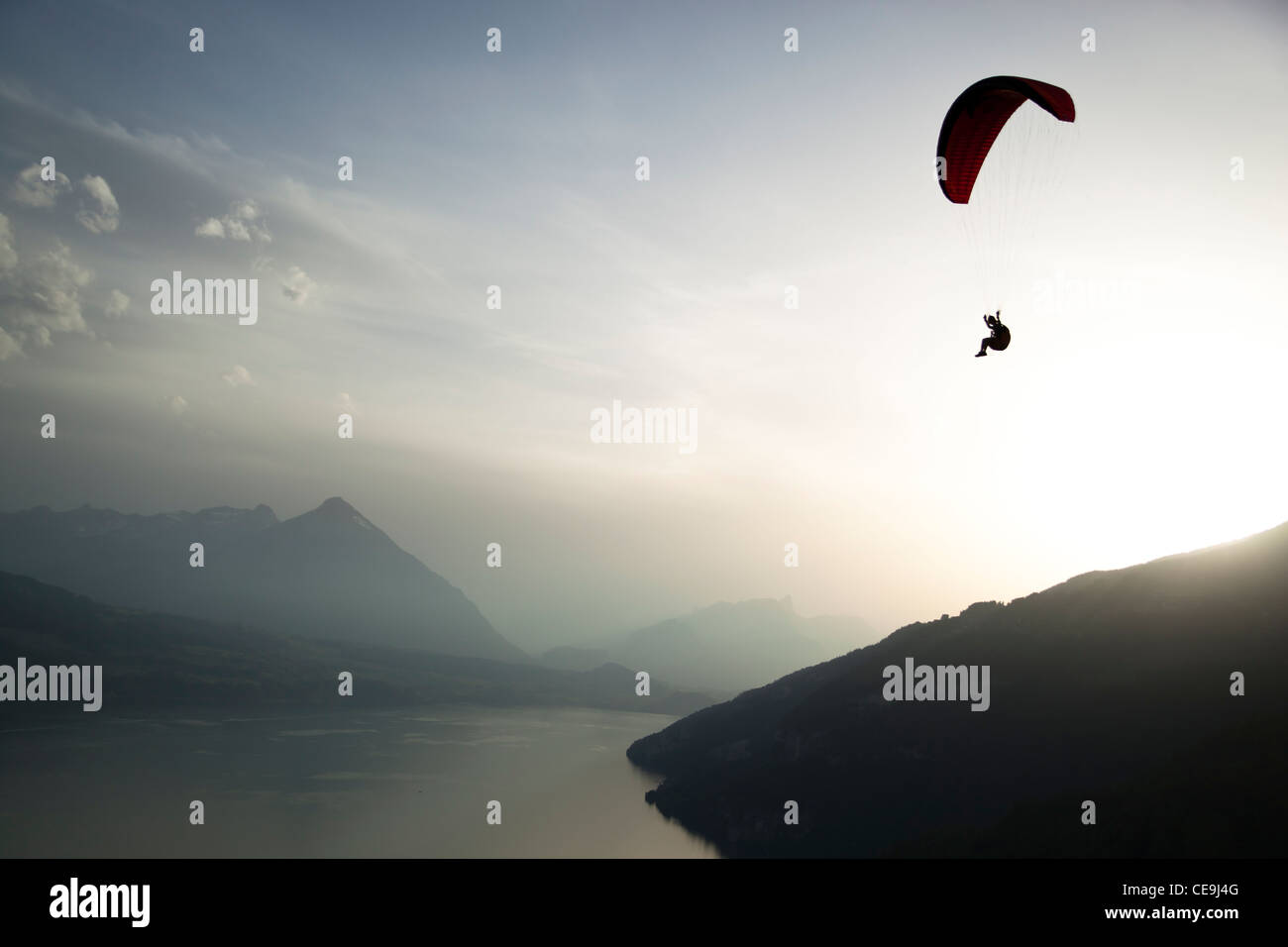 Acro paraglider pilot performing tricks over Interlaken at sunset ...