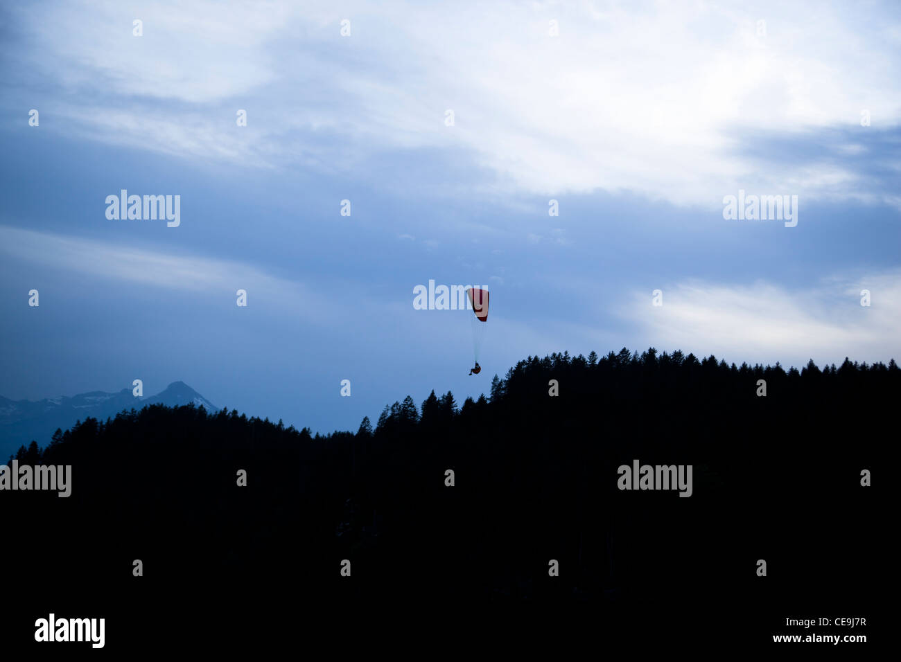 Acro paraglider pilot performing tricks over Interlaken in the evening ...