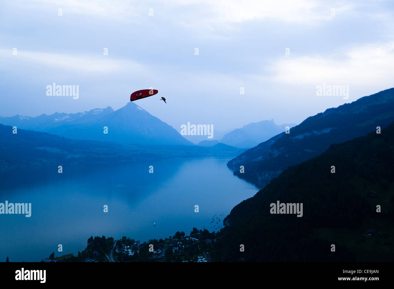 Acro paraglider pilot performing tricks over Interlaken in the evening ...