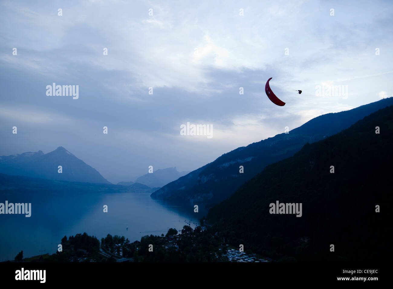 Acro paraglider pilot performing tricks over Interlaken in the evening ...
