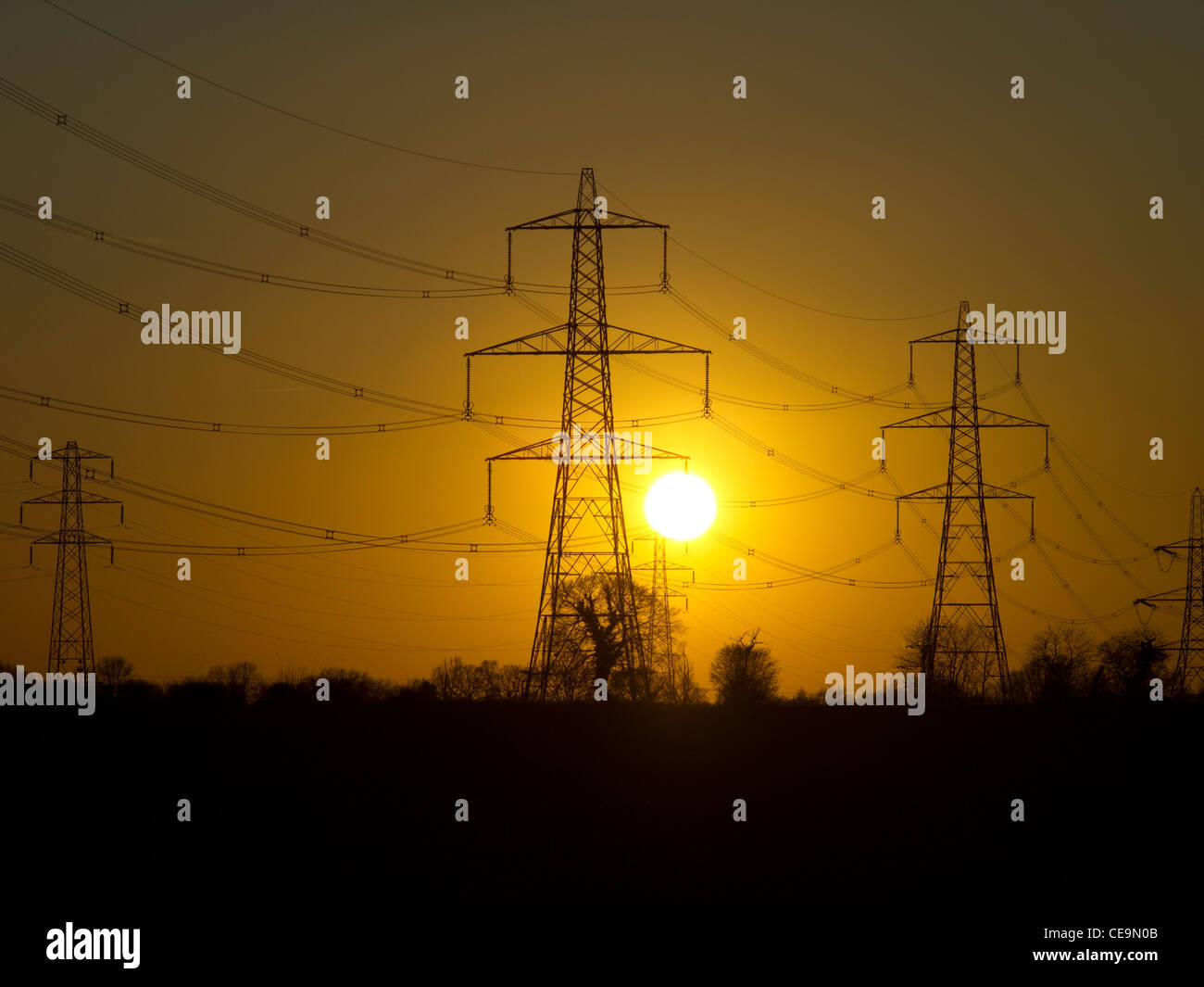 The sun, setting behind electrical pylons in the countryside Stock ...