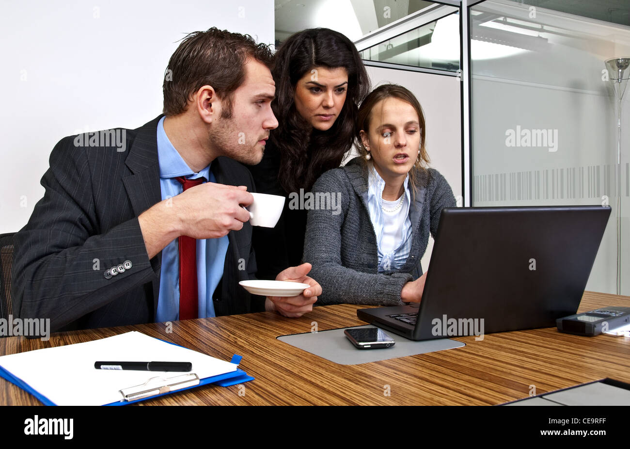 Three staff members discussing business matters whilst browsing a ...