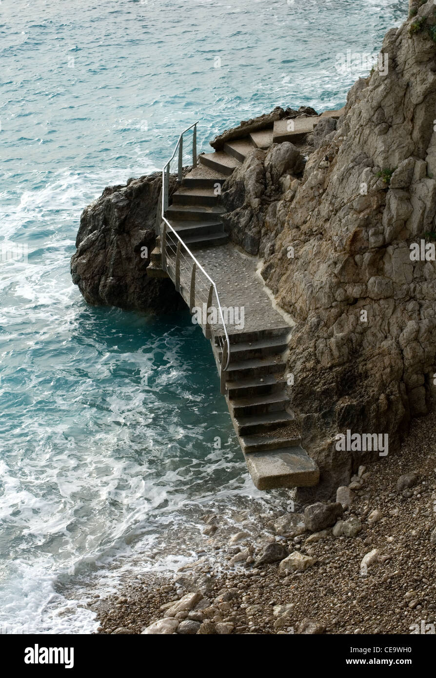 Steps winding above the Mediterranean Sea around a rock cliff in Monaco ...