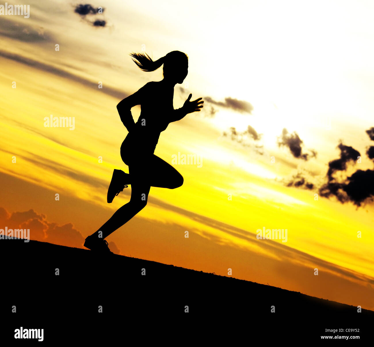 Silhouette of a beautiful woman running down the hill against yellow ...