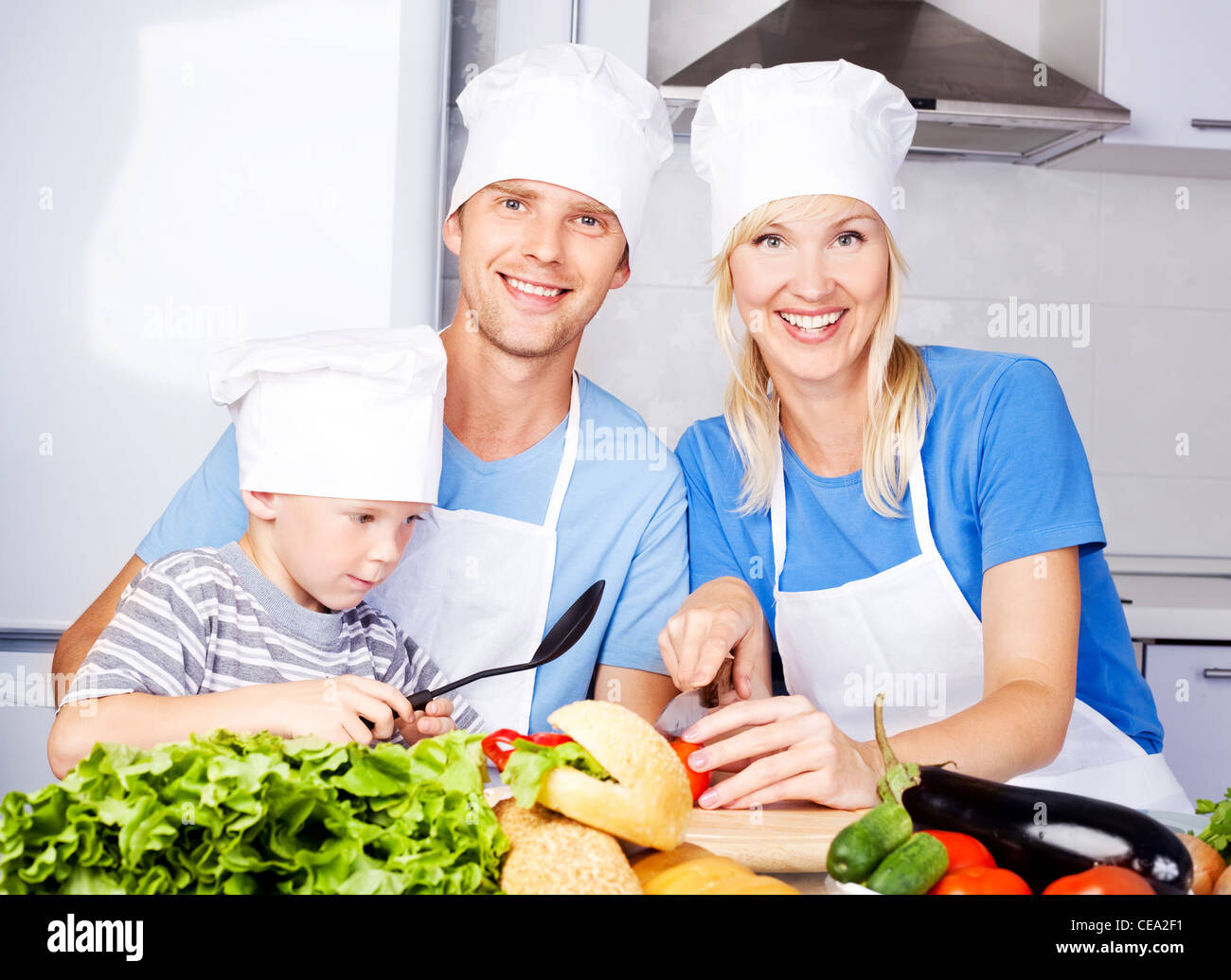 young family; father, mother and their five year old son cook together ...
