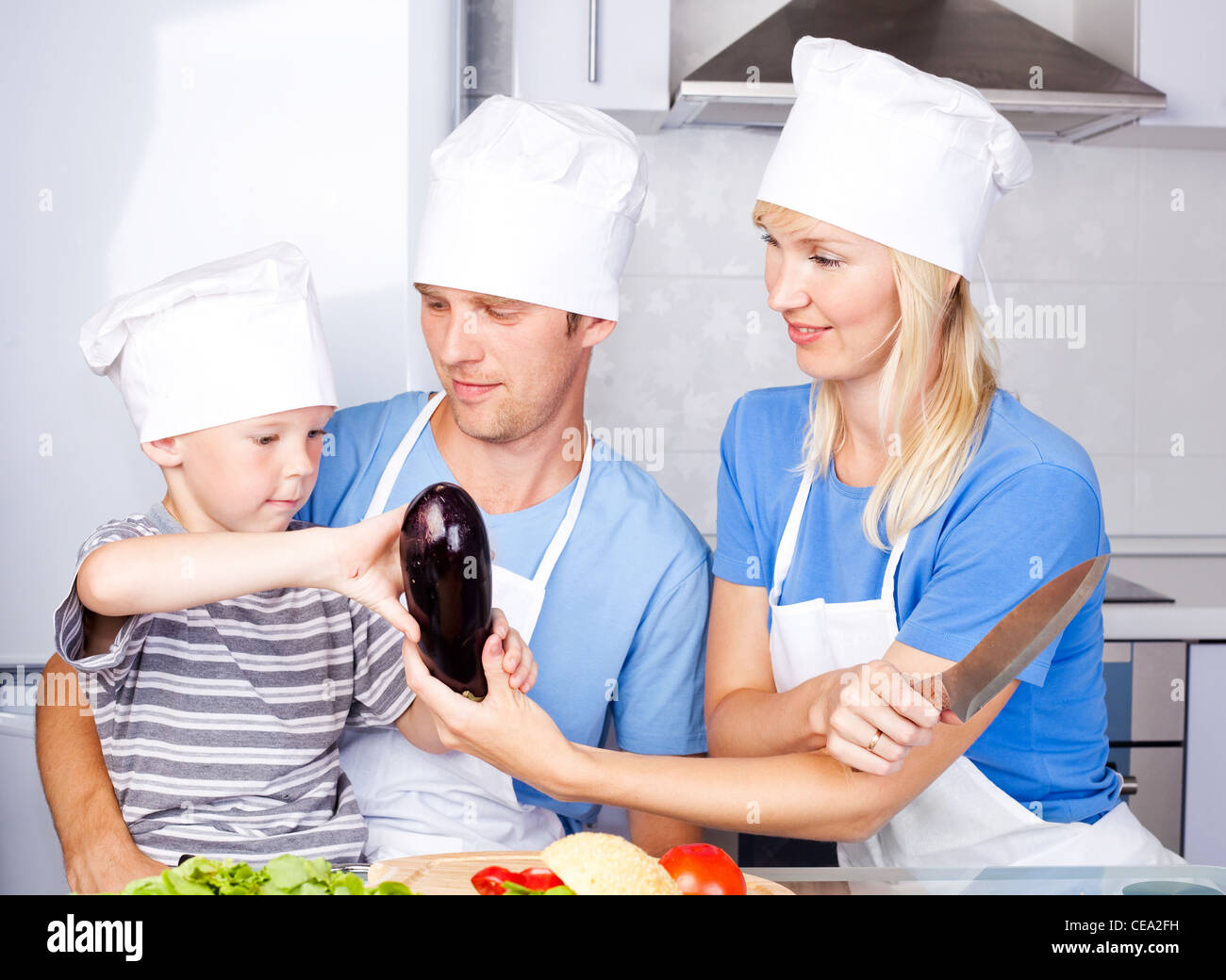 young family; father, mother and their five year old son cook together ...