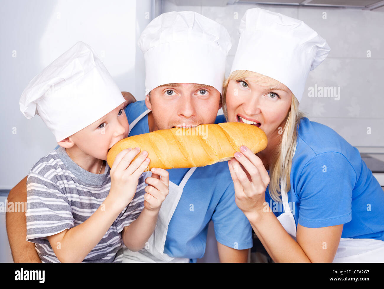 young family; father, mother and their five year old son eating bread ...