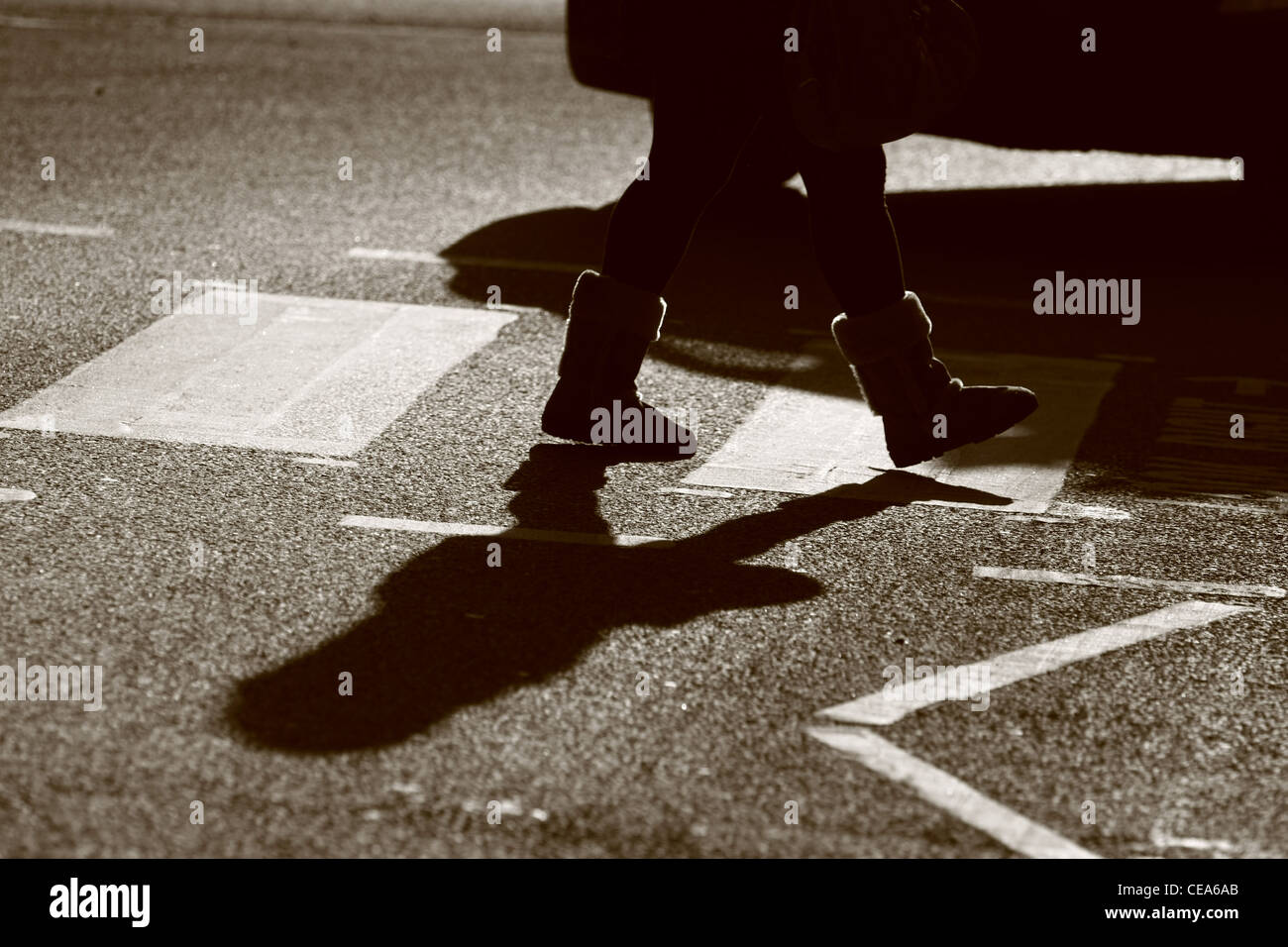 The legs of a woman as she crosses a road at a zebra crossing in London ...