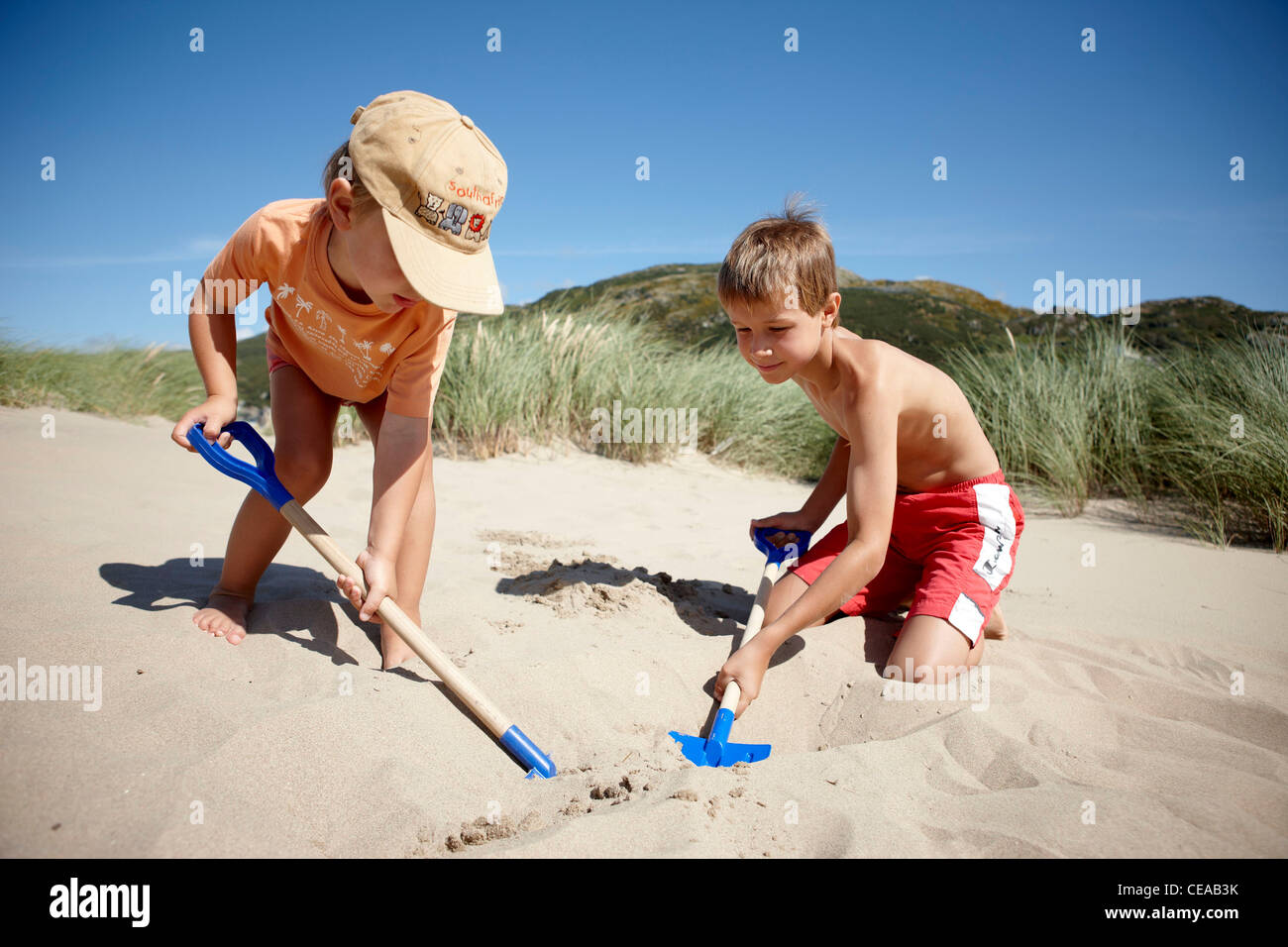 Children digging a hole on a beach in Barmouth Stock Photo - Alamy
