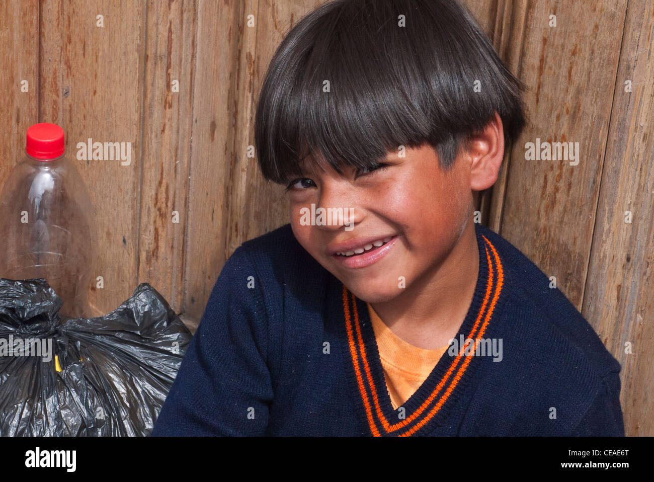 A 4-5 year old Hispanic boy smiles as he faces forward and leans ...