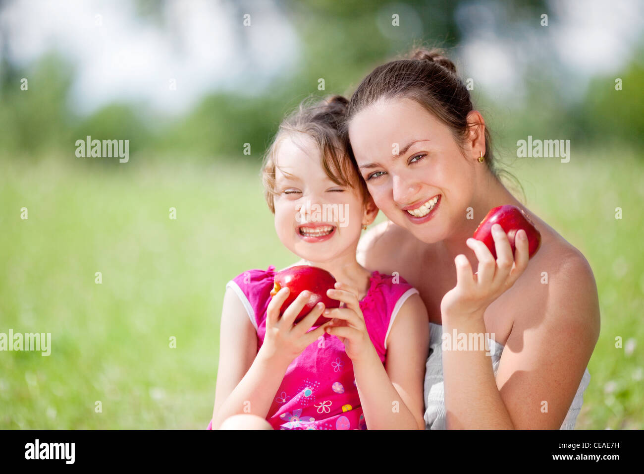 happy mother and daughter eating fruit in the park Stock Photo - Alamy