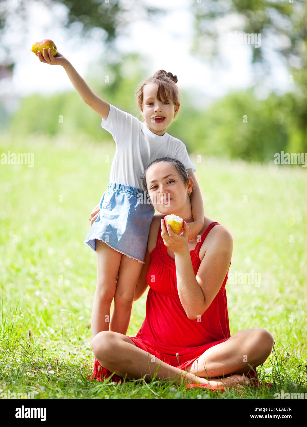 happy mother and daughter eating fruit in the park Stock Photo - Alamy