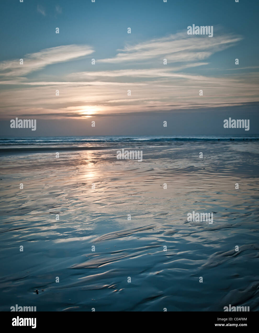 The sunset on a North Devon beach, with the sun's reflection glistening ...