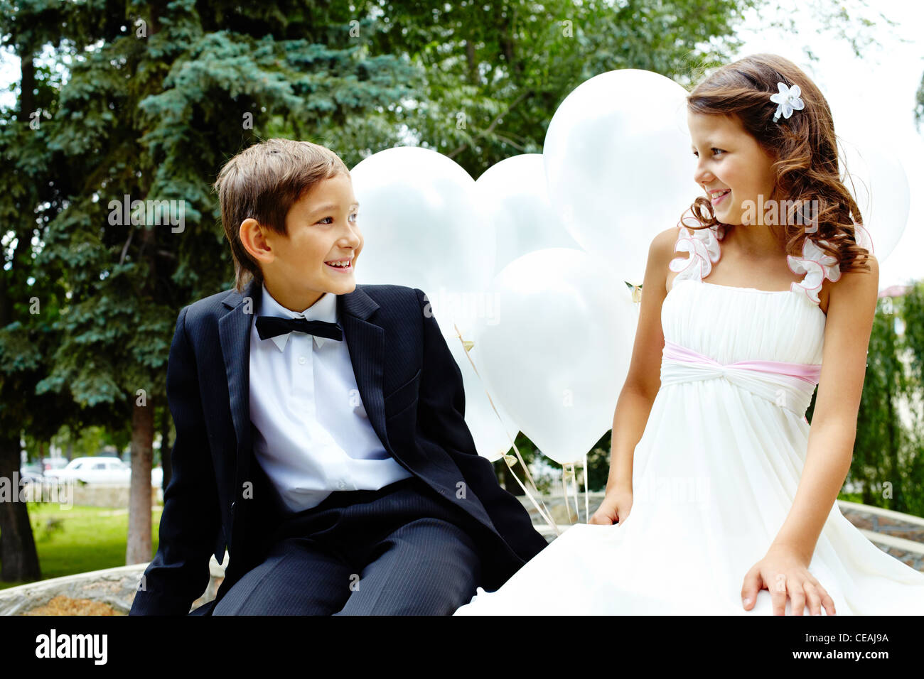 Portrait of children bride and groom with balloons chatting in park ...