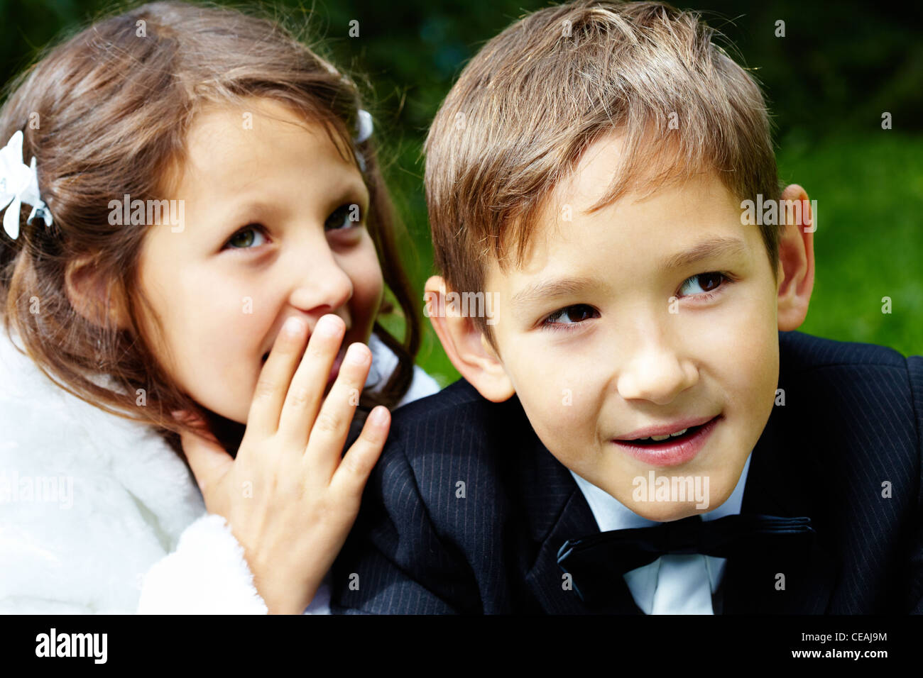 Portrait of boy groom looking aside with his bride telling him secret ...