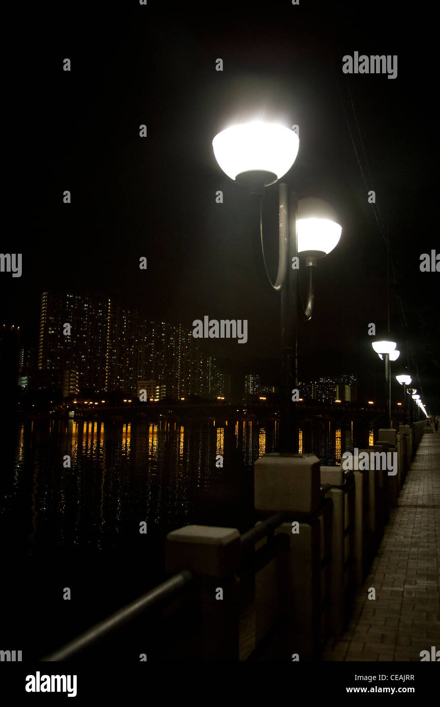 Shing Mun River walk way with lights of tower blocks and city lights at ...