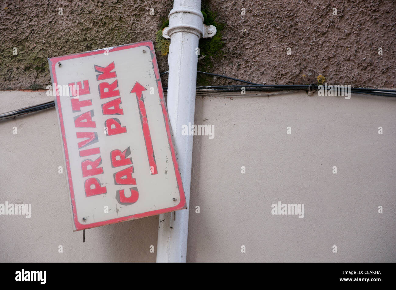 Private car park sign hanging on side so direction arrow points up to ...