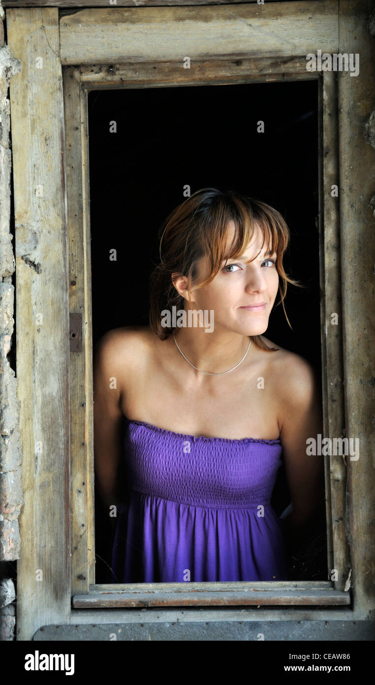 Portrait of a content young woman standing in window frame Stock Photo ...