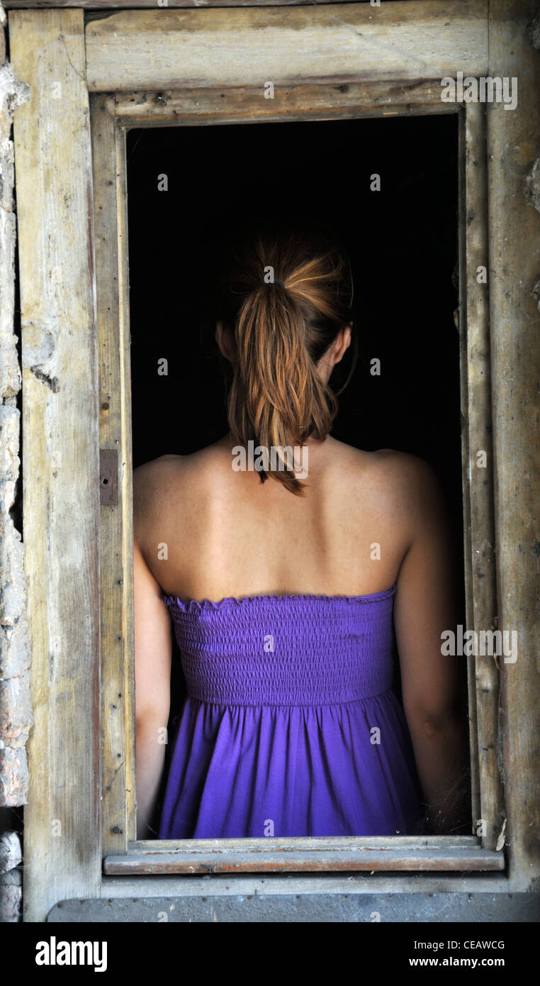 Young woman standing in window frame rear view Stock Photo - Alamy