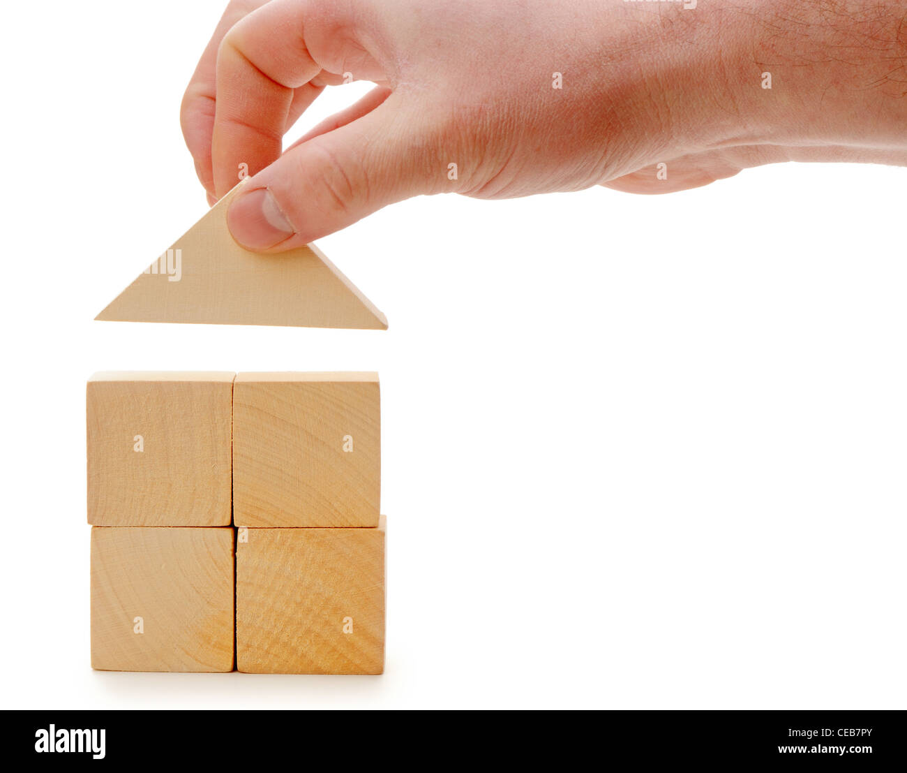 The hand establishes a toy roof on wooden cubes. Isolated on white ...