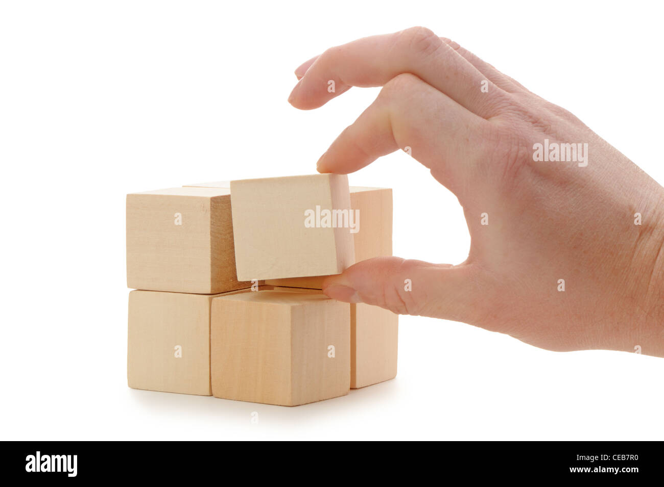 The hand establishes a wooden cube. It is isolated on a white ...