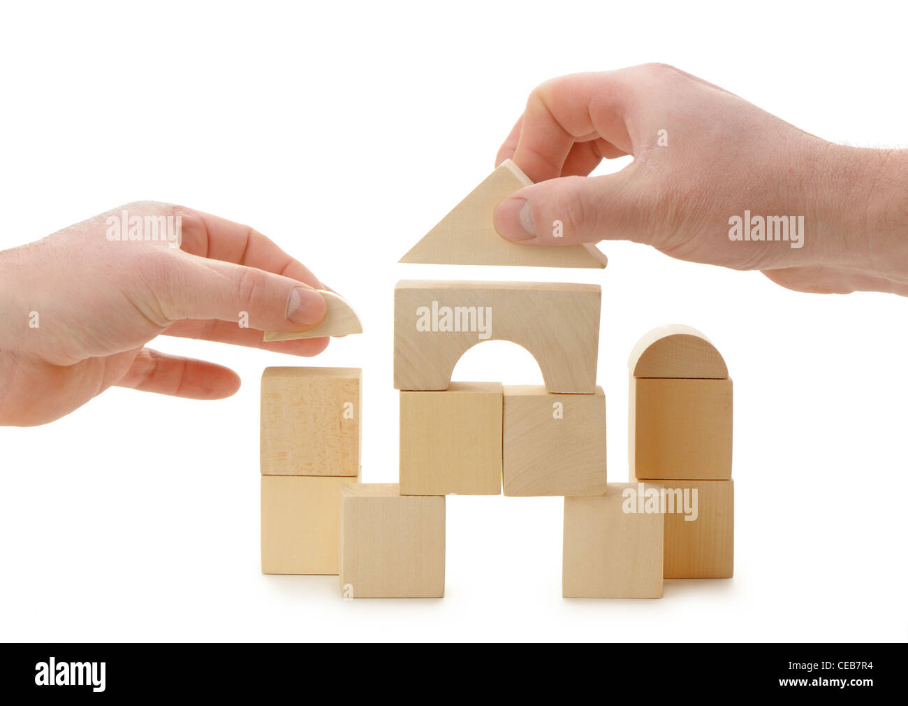 The hands establishes a toy roof on wooden cubes. Isolated on white ...