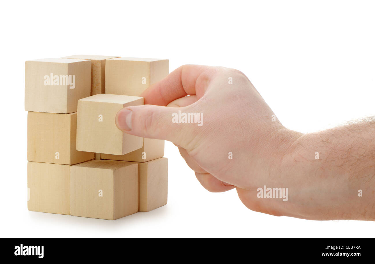 The hand establishes a wooden cube. It is isolated on a white ...
