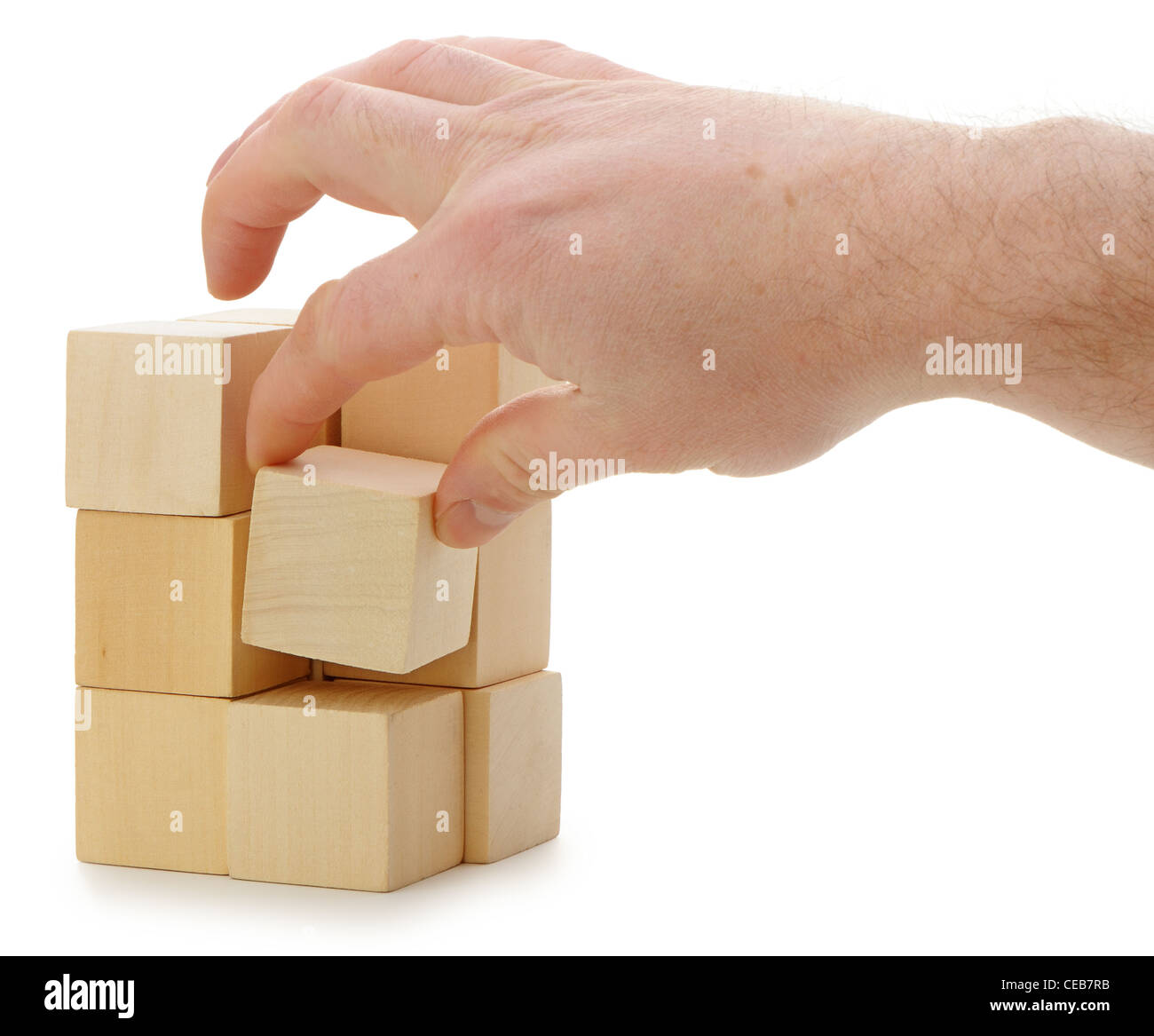 The hand establishes a wooden cube. It is isolated on a white ...
