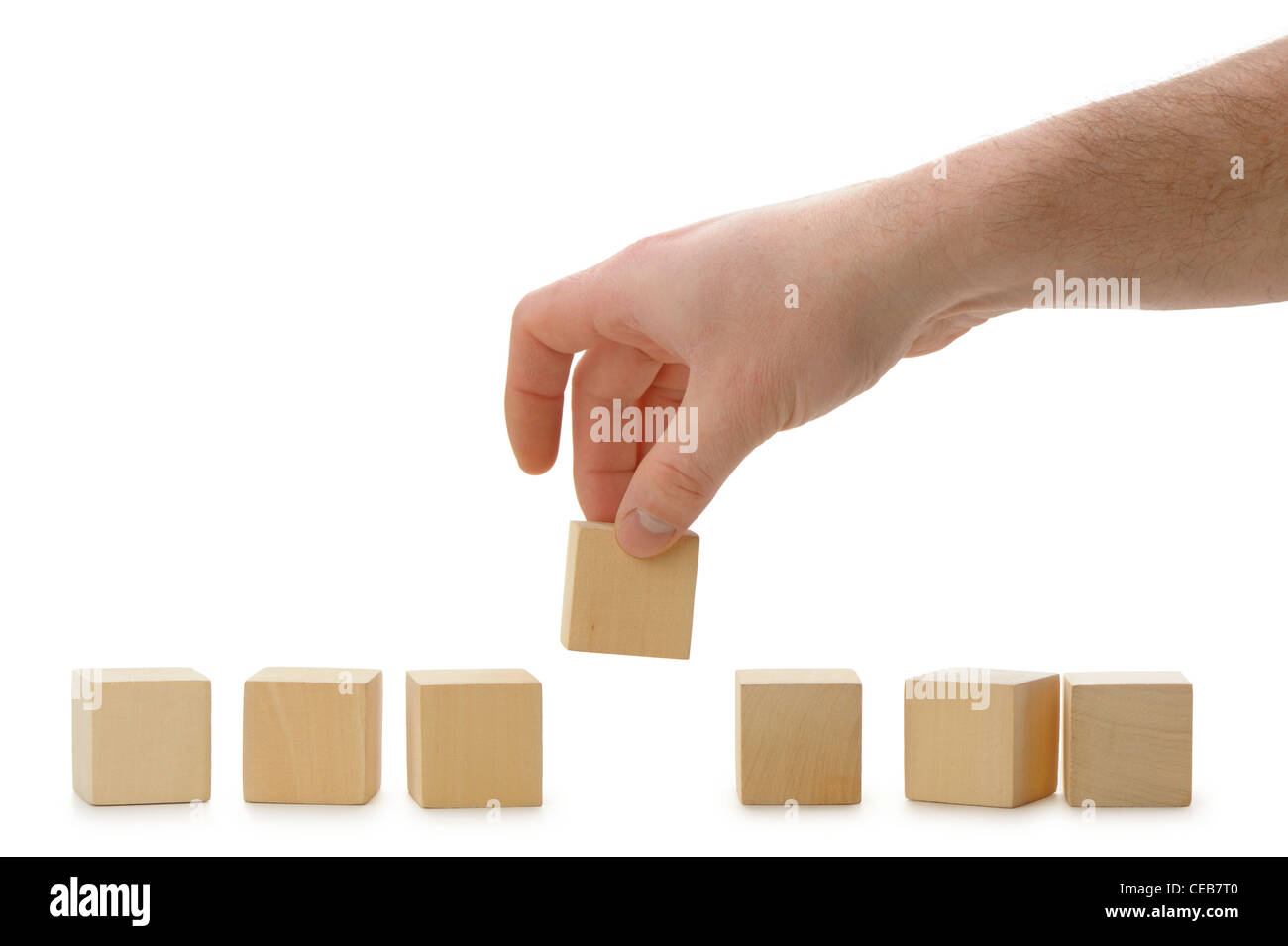 The hand establishes a wooden cube in row. It is isolated on a white ...