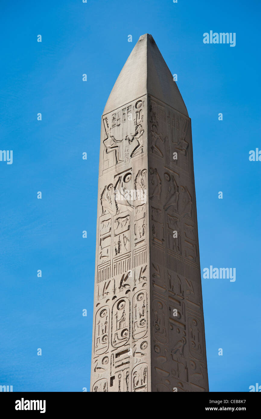 Large ancient obelisk with egyptian hieroglyphics at Karnak temple in Luxor against a blue sky ...