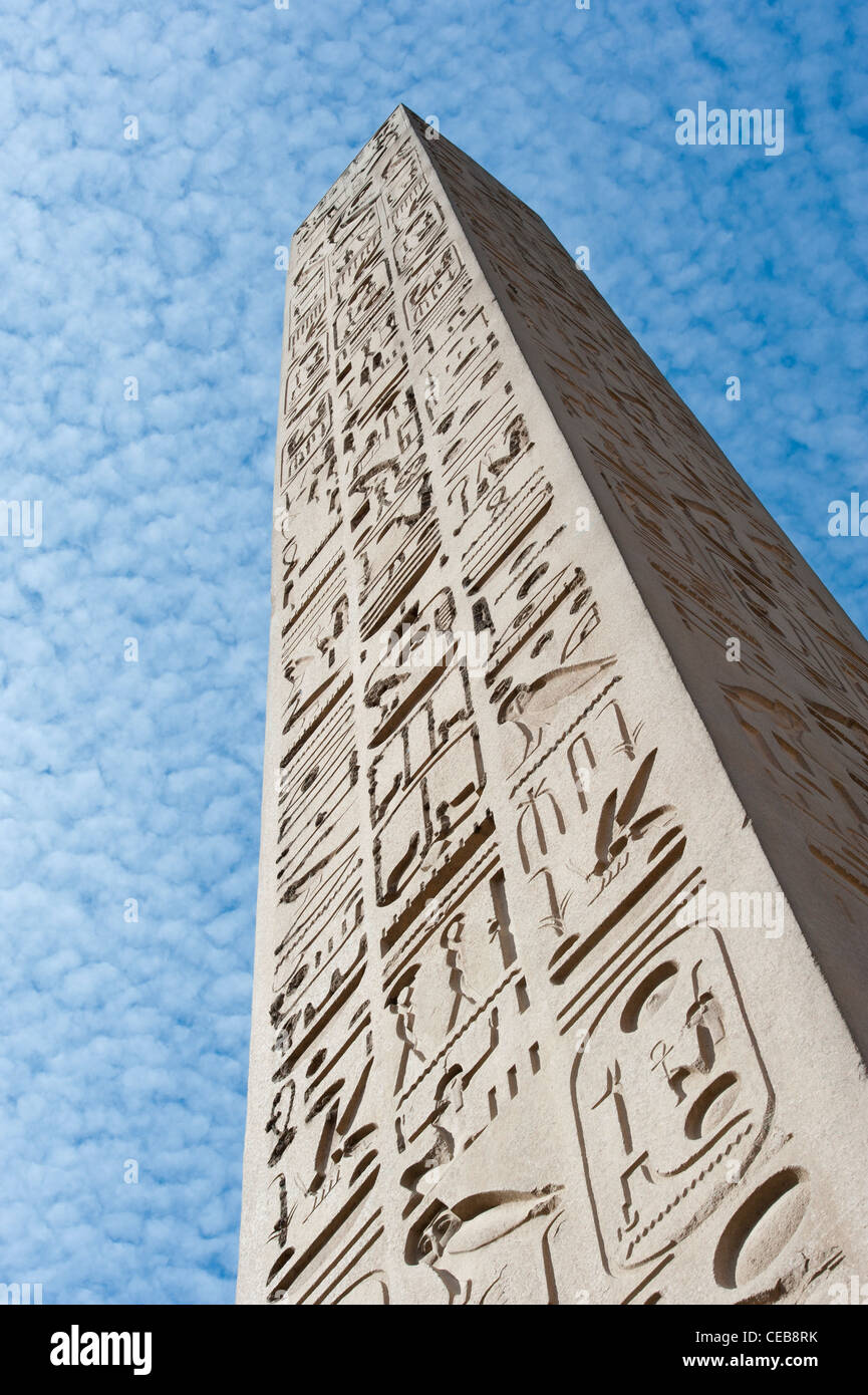 Large ancient obelisk with egyptian hieroglyphics at Karnak temple in Luxor against a blue sky ...