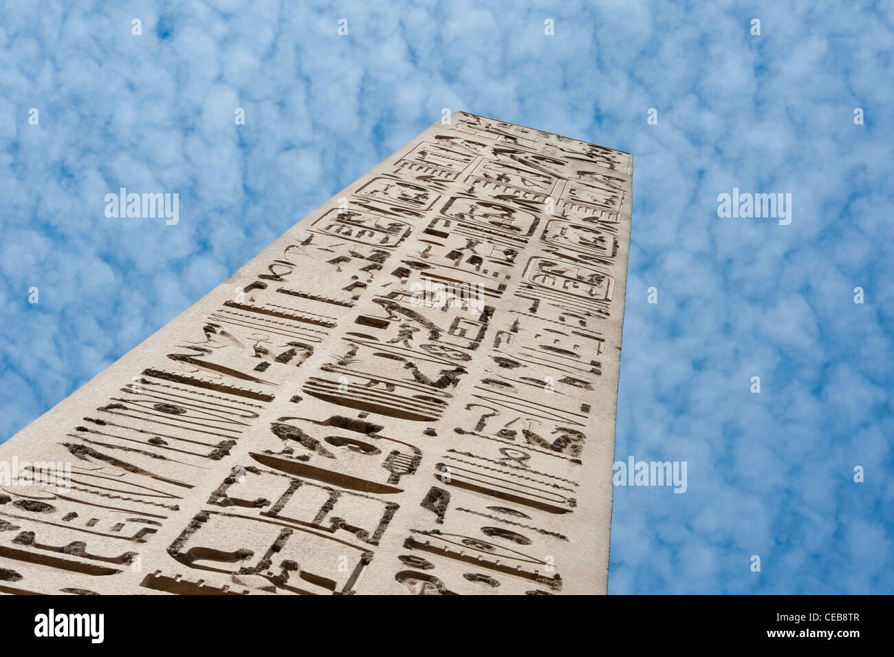 Large ancient obelisk with egyptian hieroglyphics at Karnak temple in Luxor against a blue sky ...