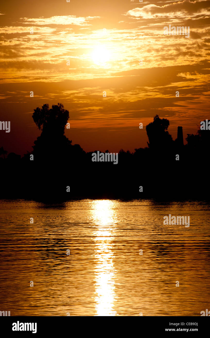 Beautiful sunset over a large river with a tree-lined river bank and ...