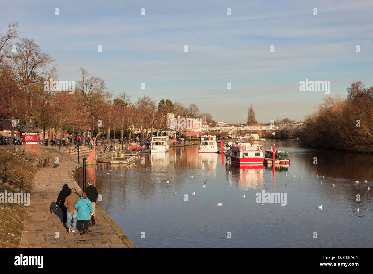 People walking along River Dee riverside walk with pleasure boats by ...