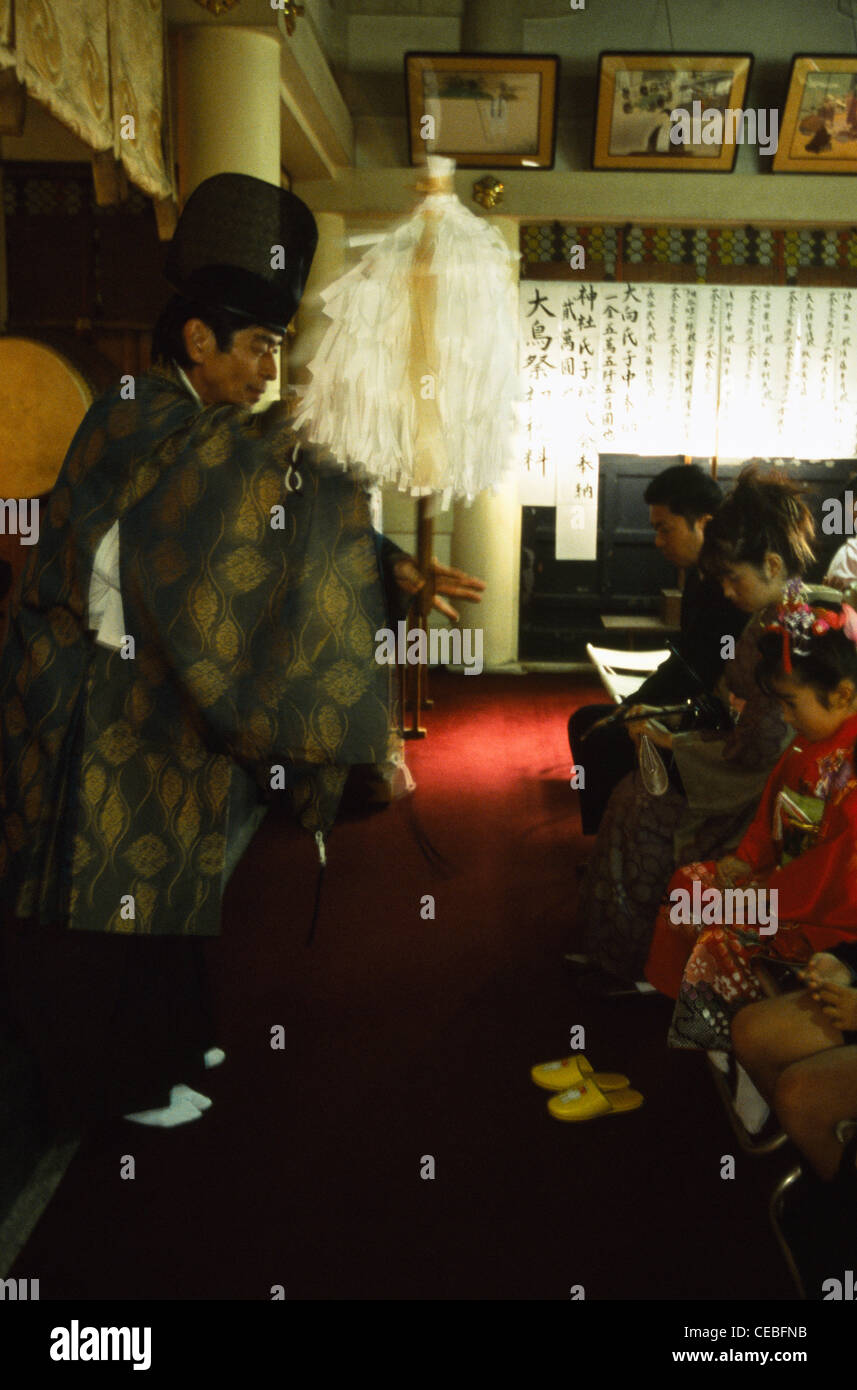 A Shinto priest performs a purification ritual by waiving a harai-gushi ...