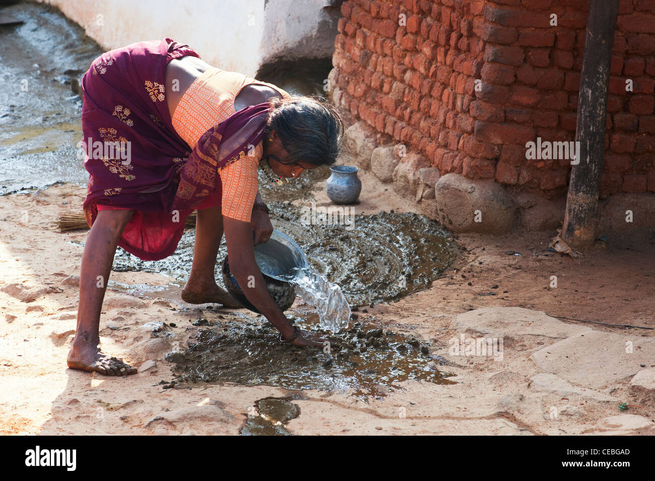 Indian woman spreading watered down cow dung outside the front of her ...