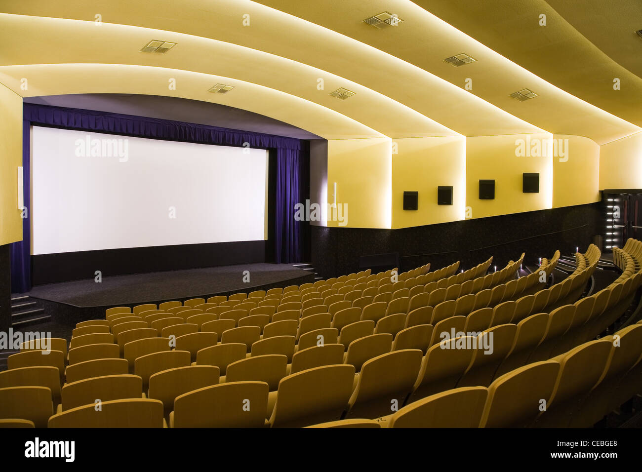 Empty cinema auditorium with line of chairs and projection screen ...
