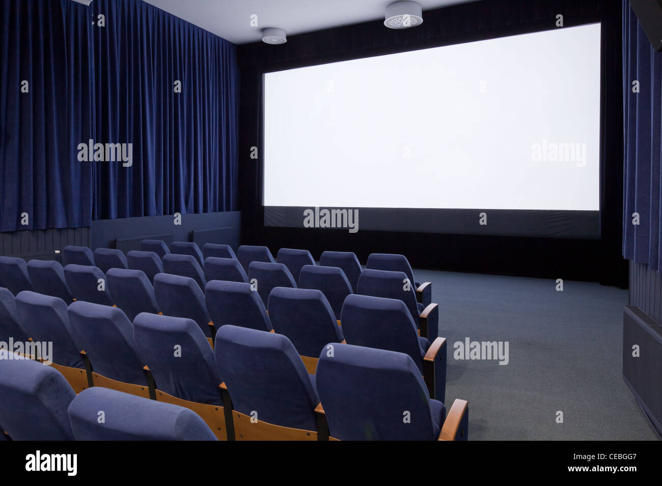 Empty cinema auditorium with line of chairs and projection screen ...