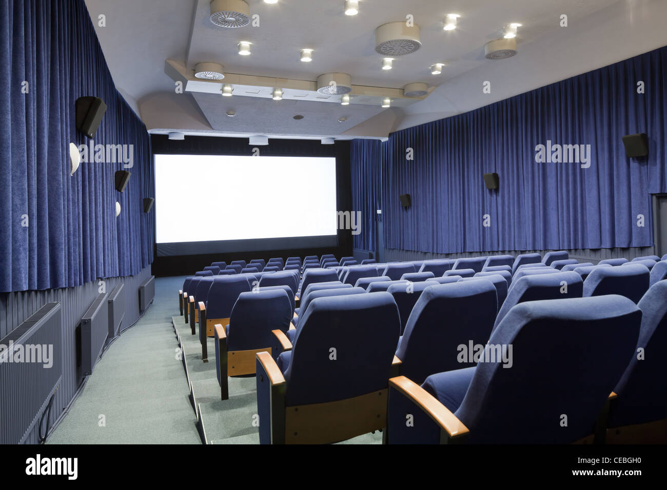 Empty cinema auditorium with line of chairs and projection screen ...