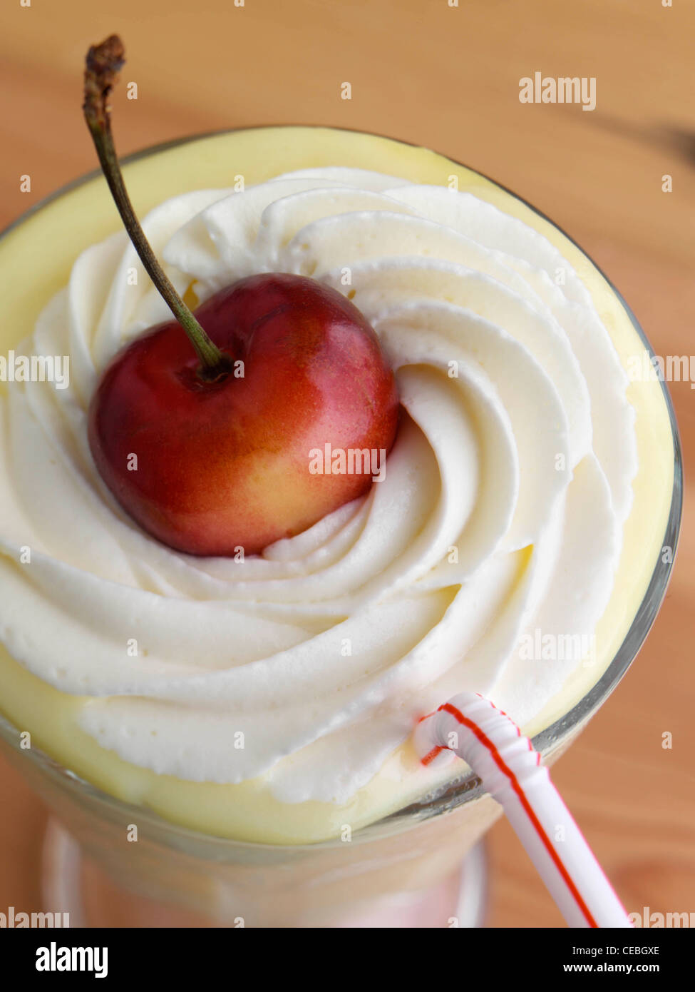Banana milkshake with whipped cream topping and a ripe cherry on top ...