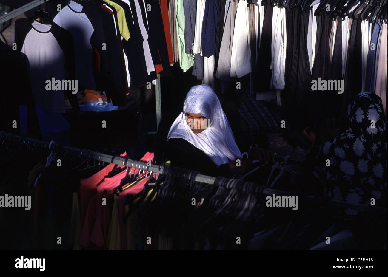 A young Palestinian woman wearing traditional Hijab in a clothing stall ...