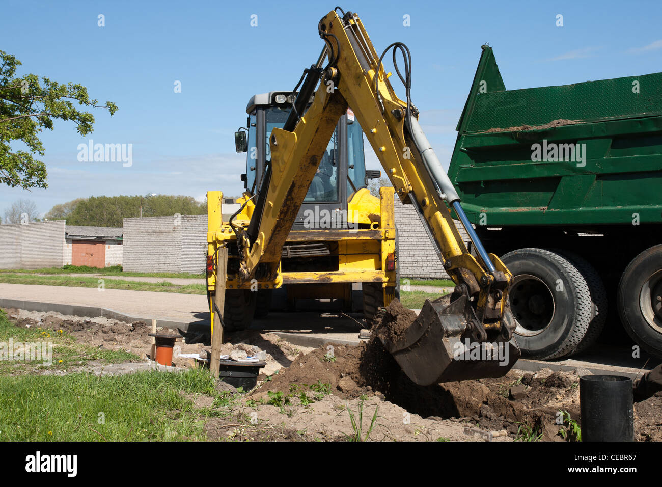 Excavator loading dumper truck tipper with sand on construction site ...