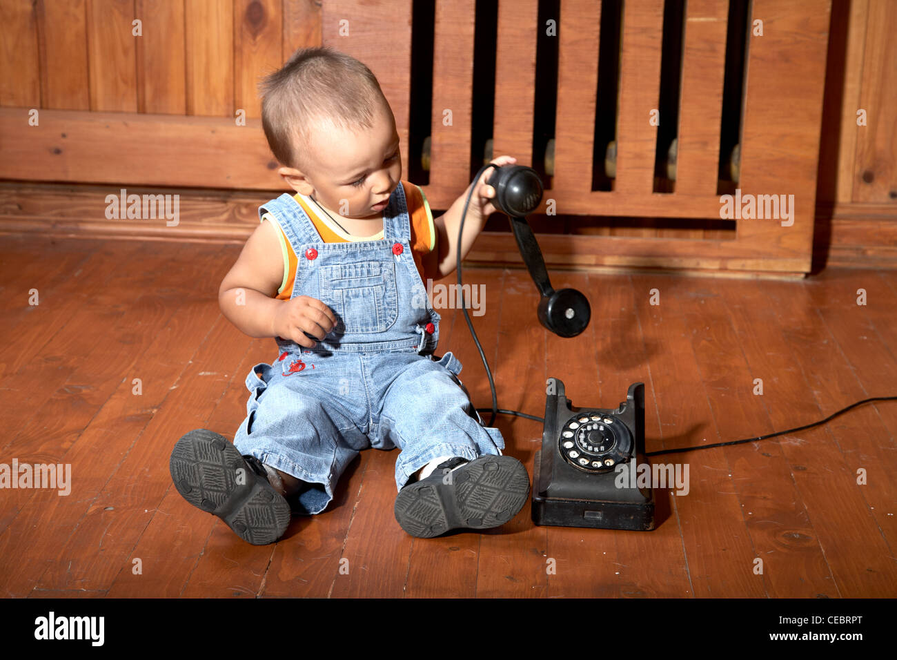 The little boy plays old phone sitting on a floor Stock Photo - Alamy
